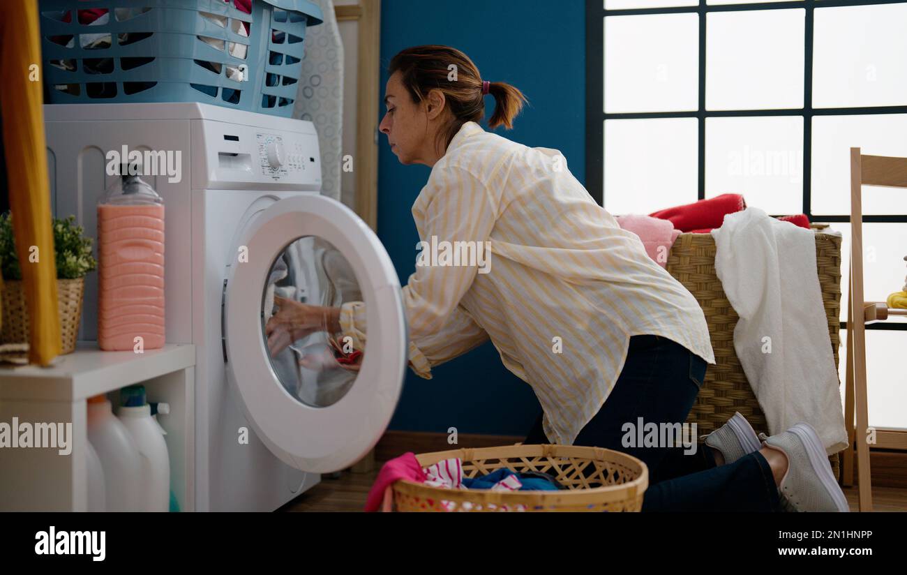Middle age hispanic woman washing clothes at laundry room Stock Photo ...