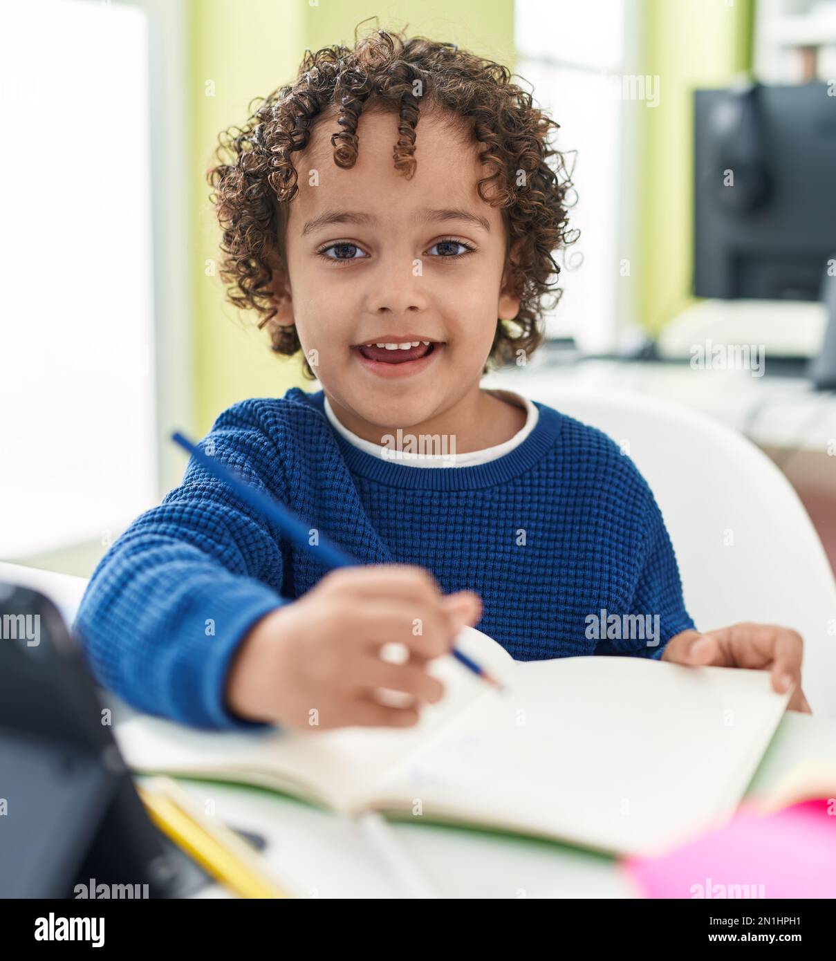Adorable hispanic boy preschool student sitting on table drawing on ...