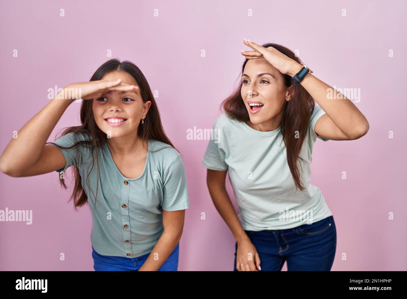 Young Mother And Daughter Standing Over Pink Background Very Happy And