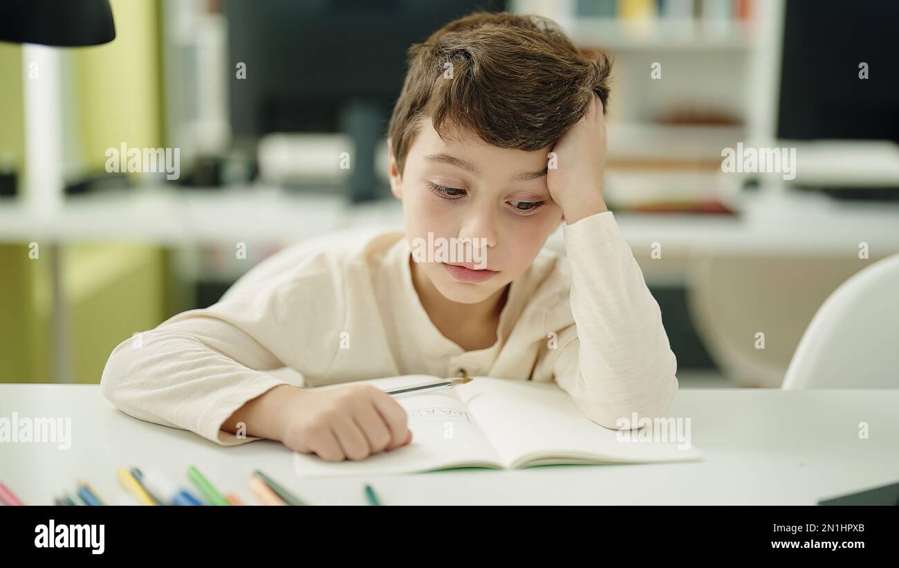 Adorable hispanic boy student reading book at classroom Stock Photo - Alamy