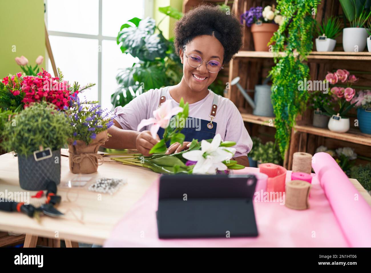 African american woman florist make bouquet of flowers watching video ...