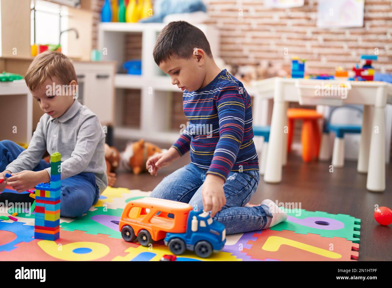 Two kids playing with construction blocks and truck toy sitting on ...
