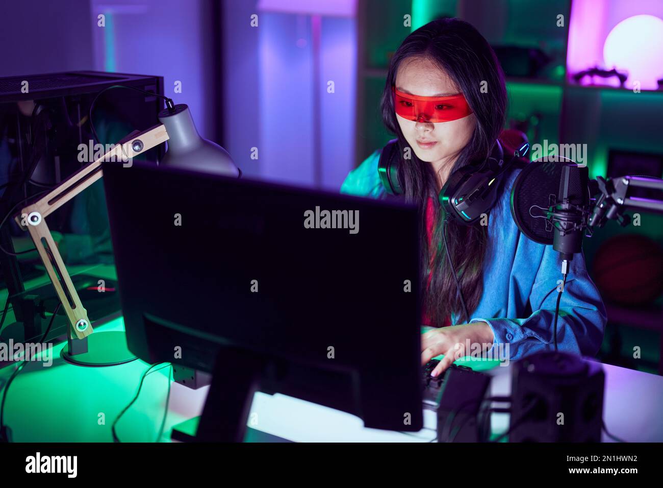 Young chinese woman streamer playing video game using virtual reality ...