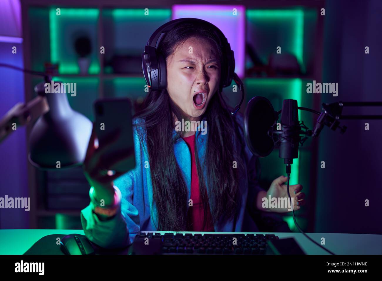 Young asian woman playing video games with smartphone angry and mad ...