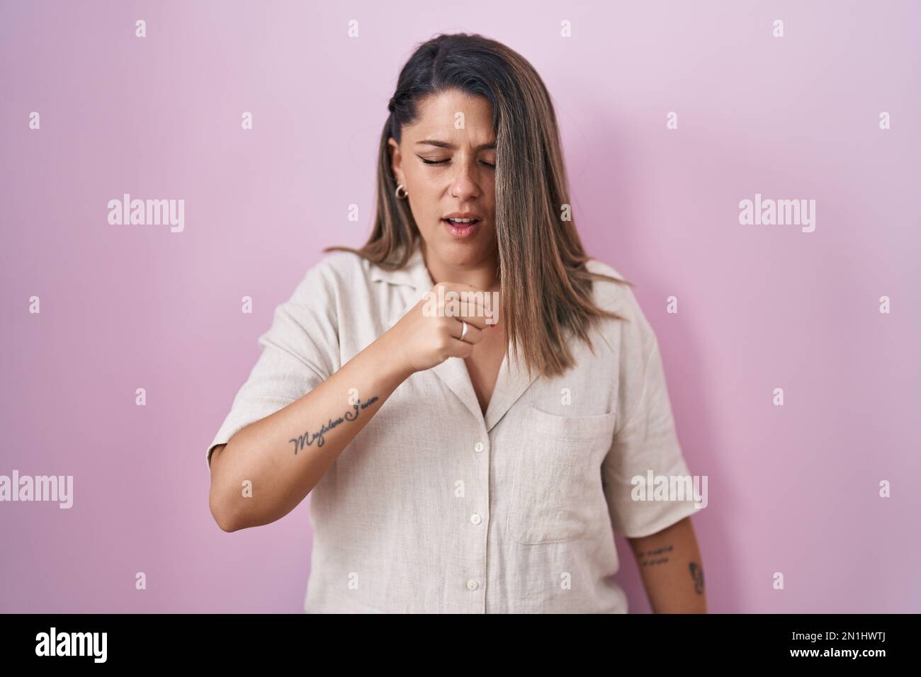Blonde woman standing over pink background feeling unwell and coughing ...