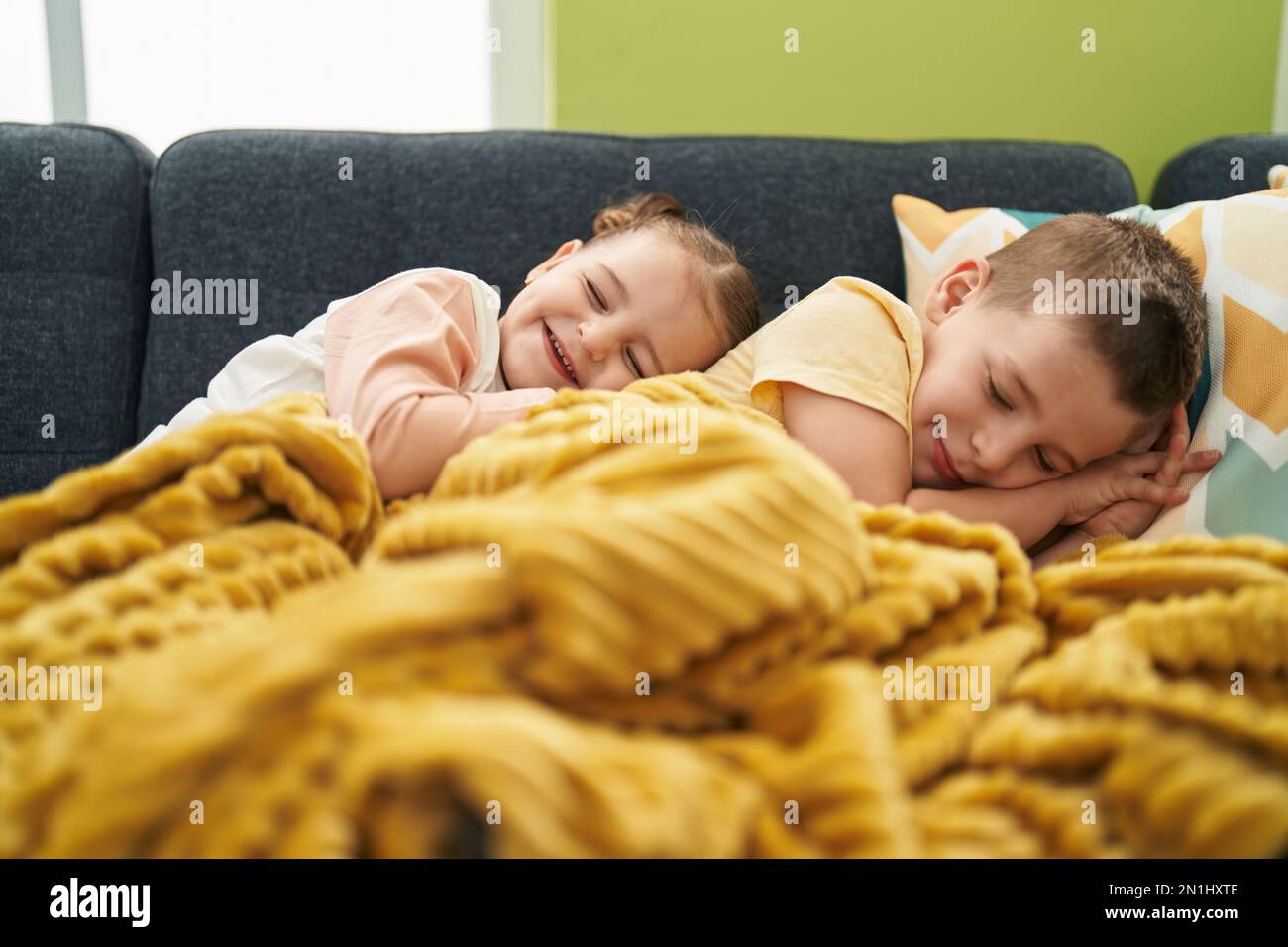 Two kids lying on sofa sleeping at home Stock Photo - Alamy
