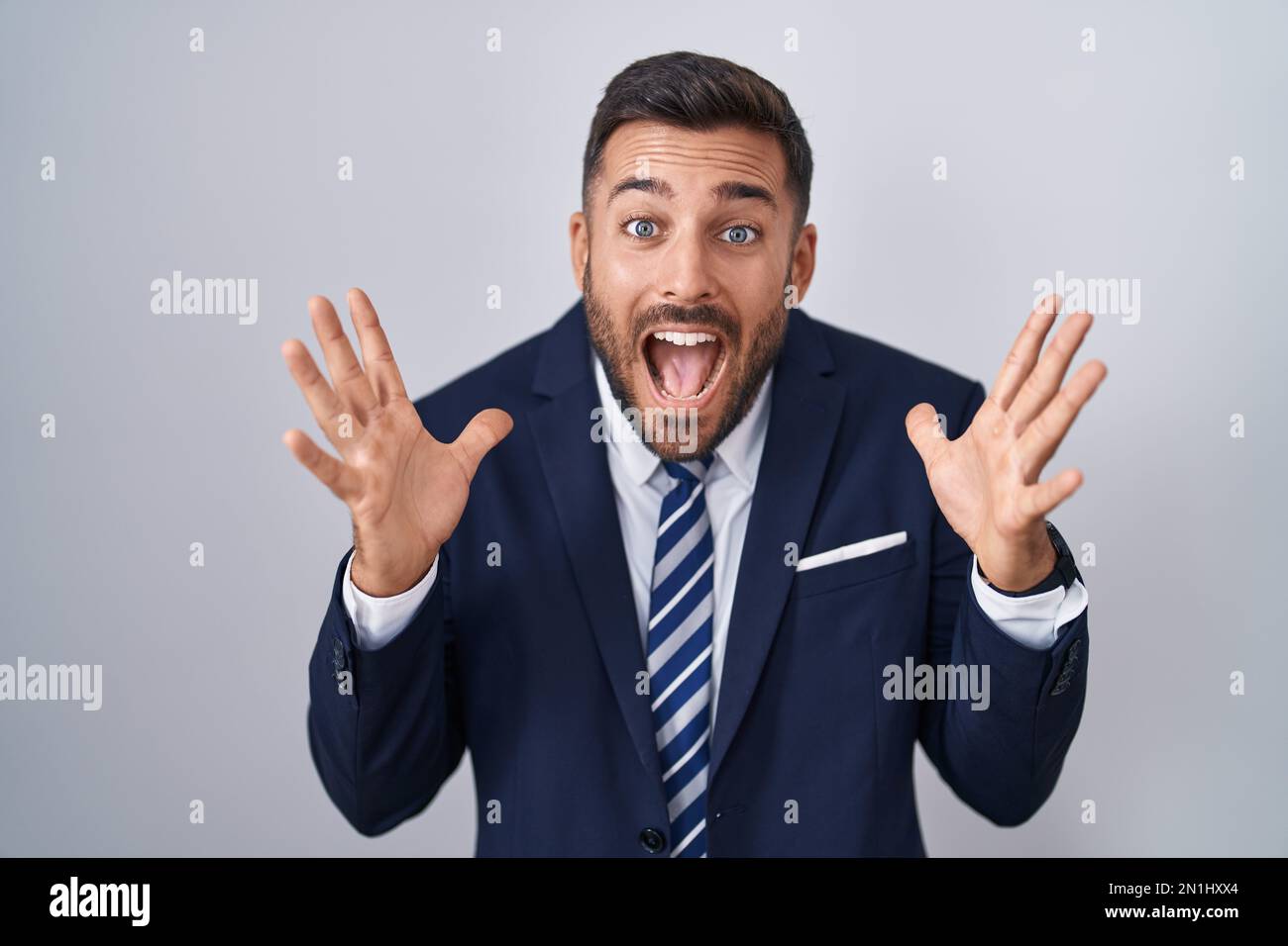 Handsome hispanic man wearing suit and tie celebrating crazy and amazed ...