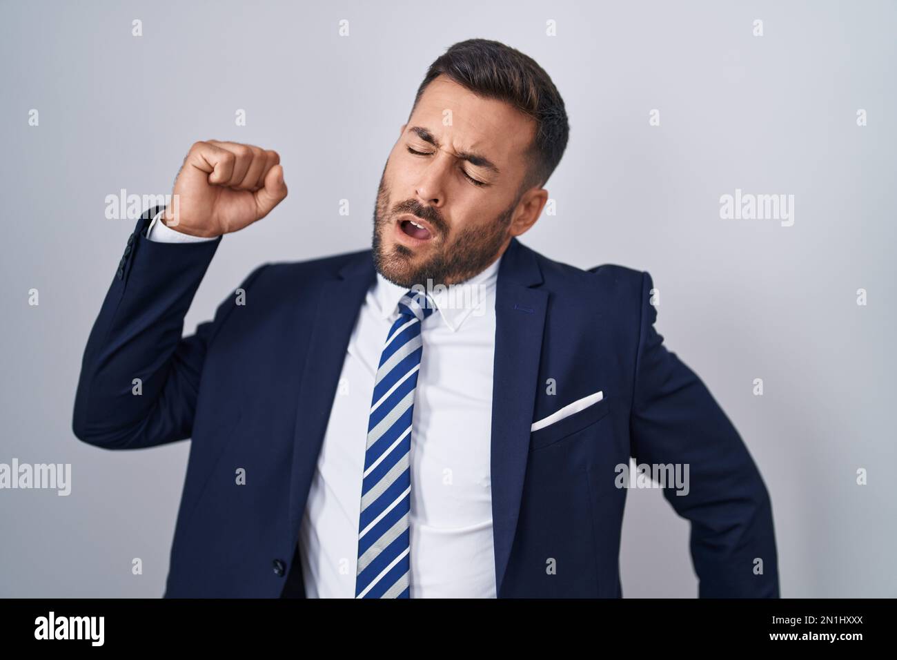 Handsome hispanic man wearing suit and tie stretching back, tired and ...