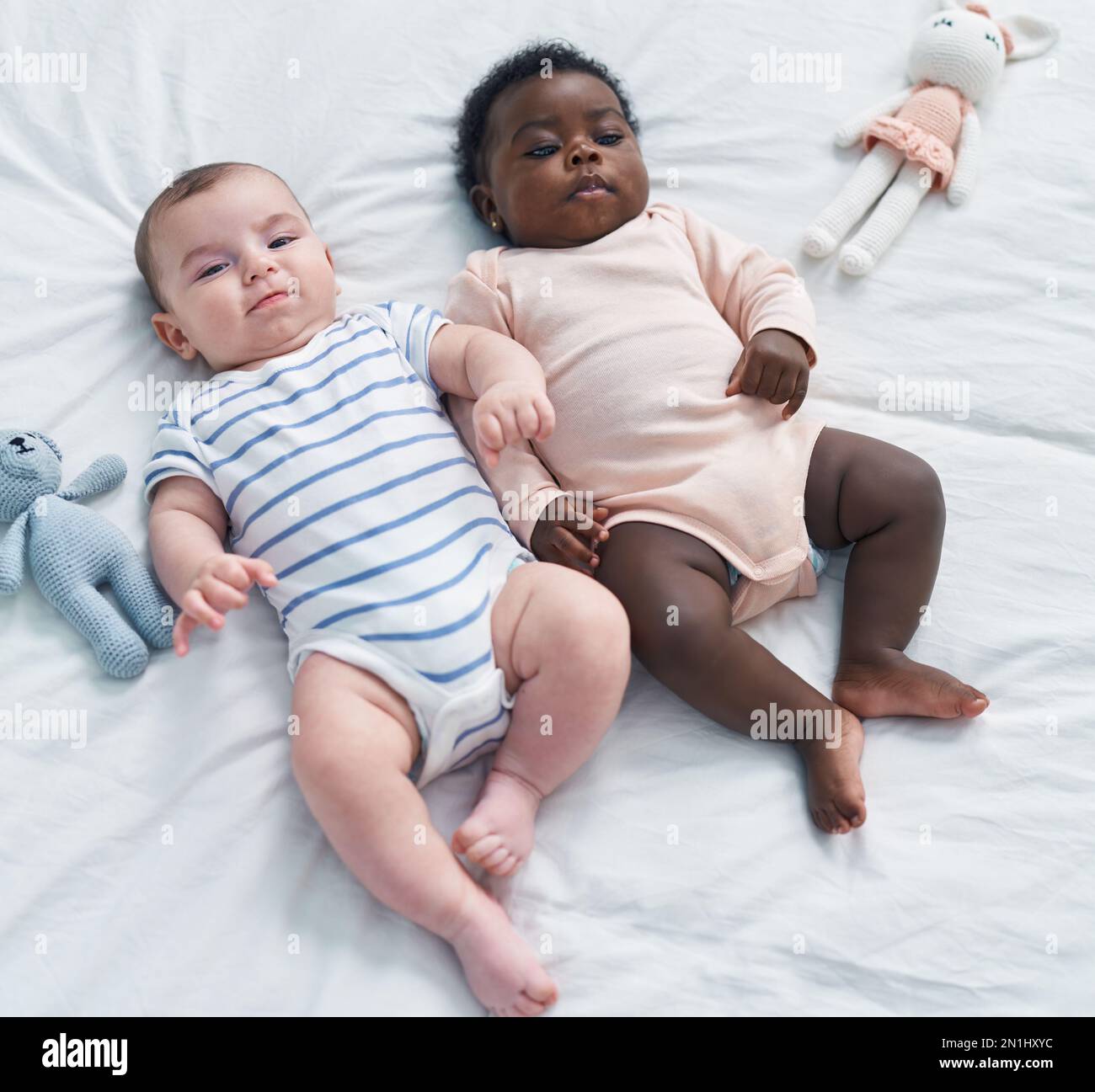 Two adorable babies lying on bed at bedroom Stock Photo - Alamy