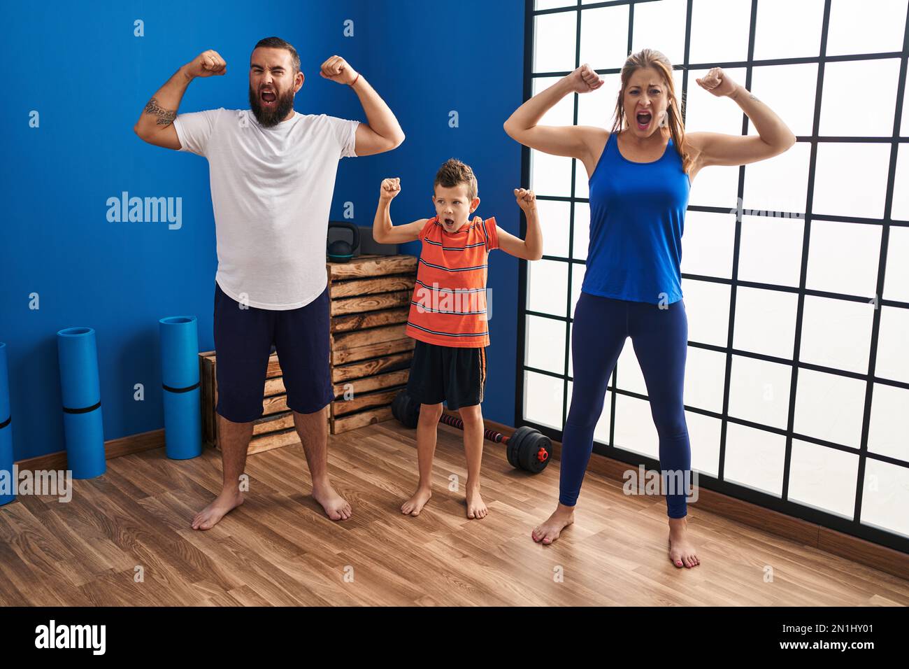 Family of three wearing sportswear at the gym angry and mad screaming ...