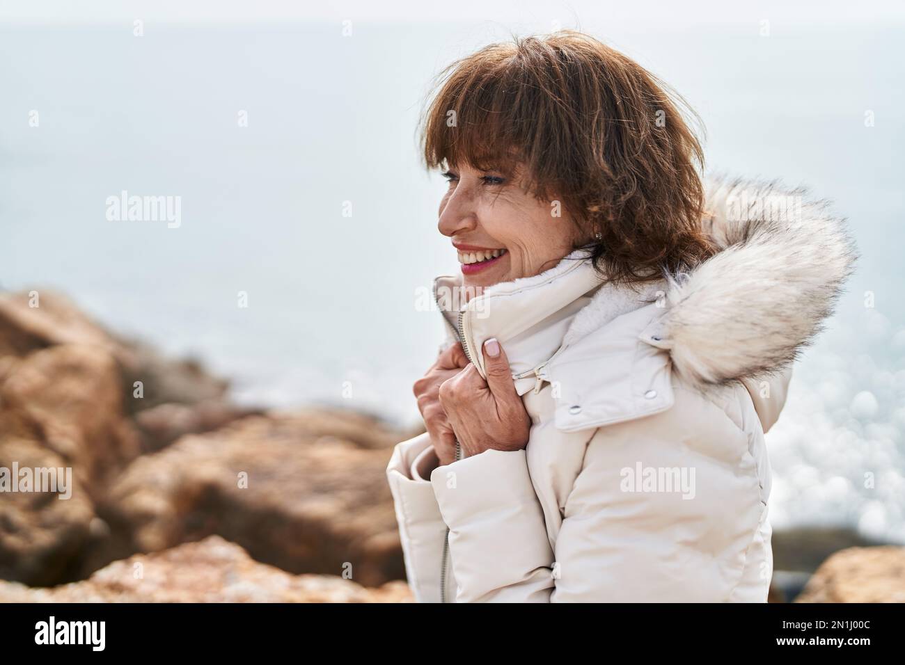 Middle age woman smiling confident freezing at seaside Stock Photo - Alamy