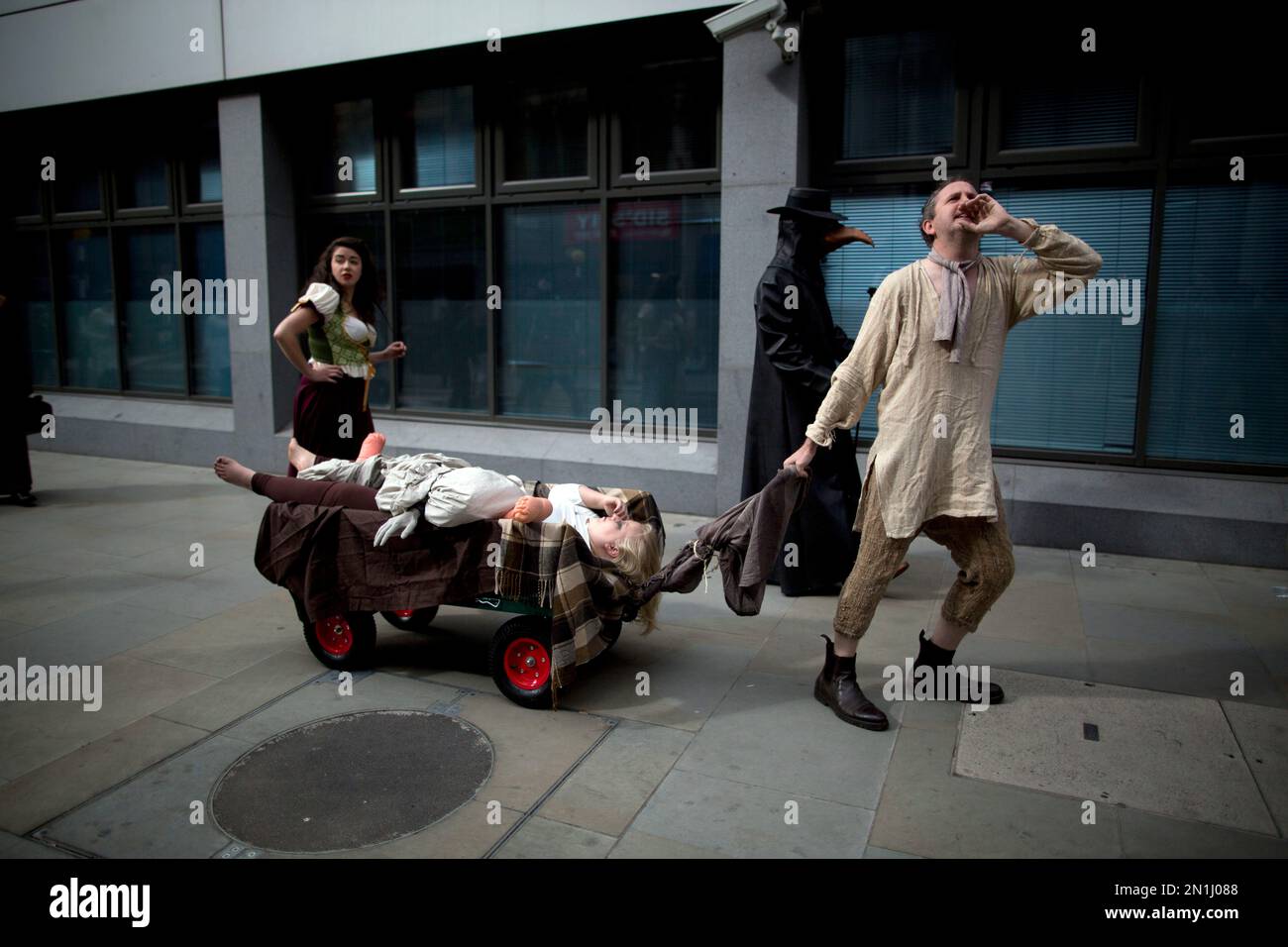 Reenactment actors dressed up in period costumes drag a dead cart ...