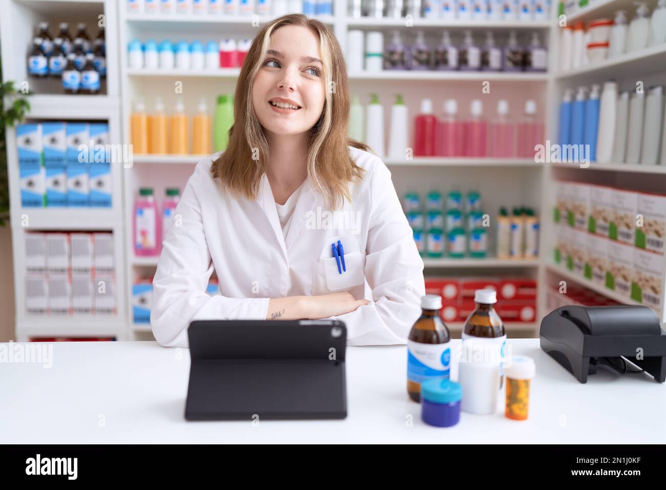 Young caucasian woman working at pharmacy drugstore using tablet ...