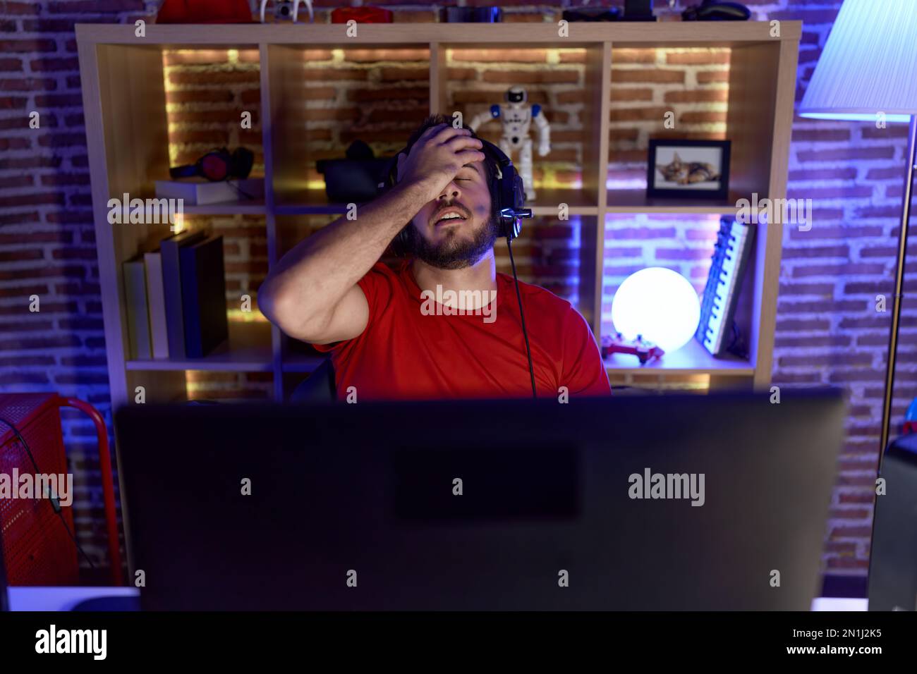 Young hispanic man streamer stressed using computer at gaming room ...