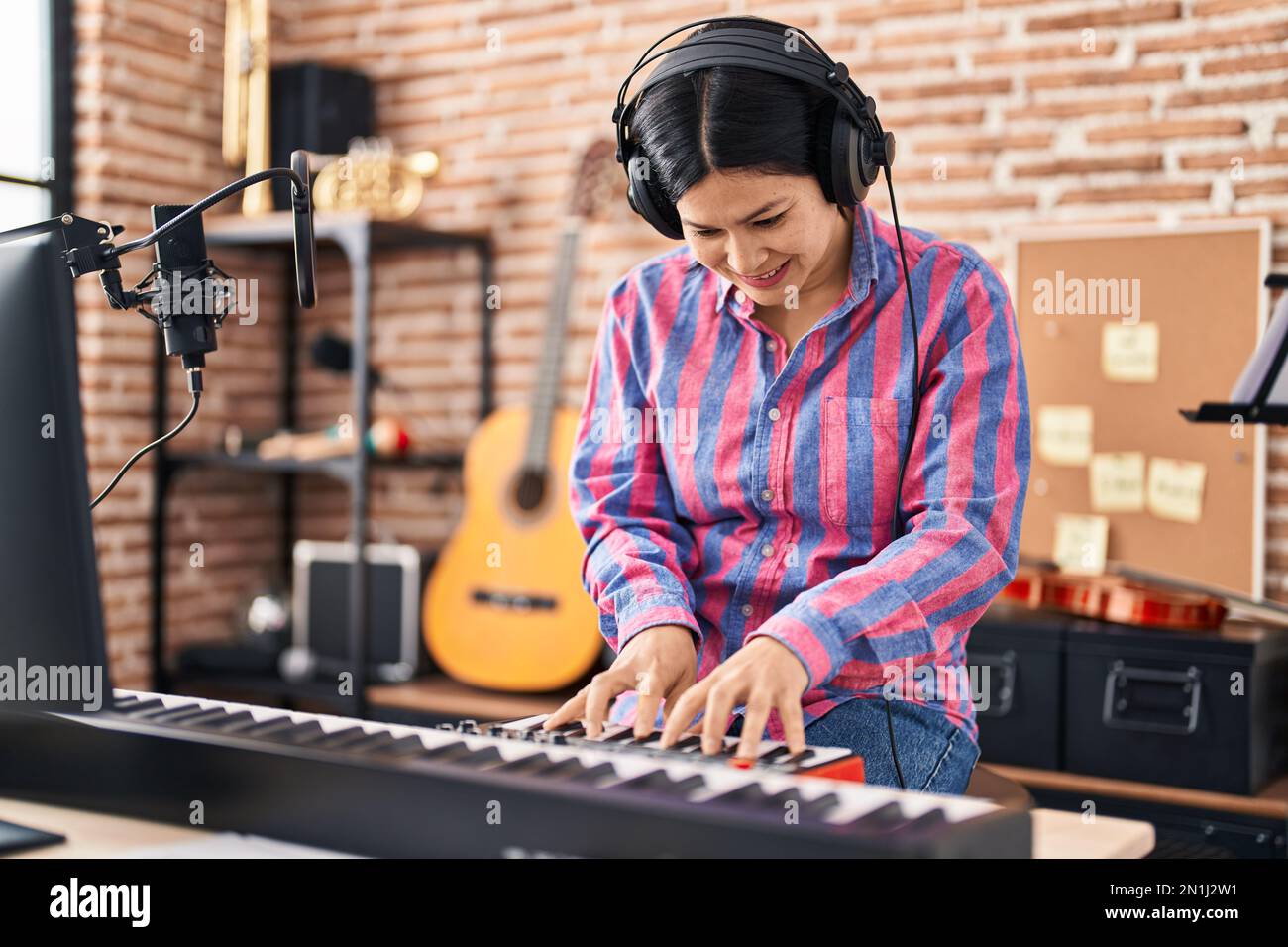 Young chinese woman musician playing piano keyboard at music studio ...