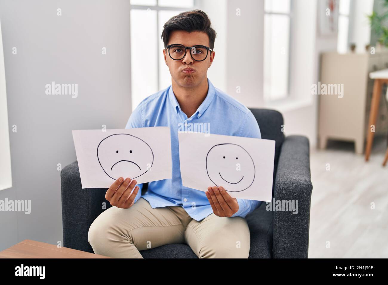 Hispanic man working on depression holding sad to happy emotion paper ...