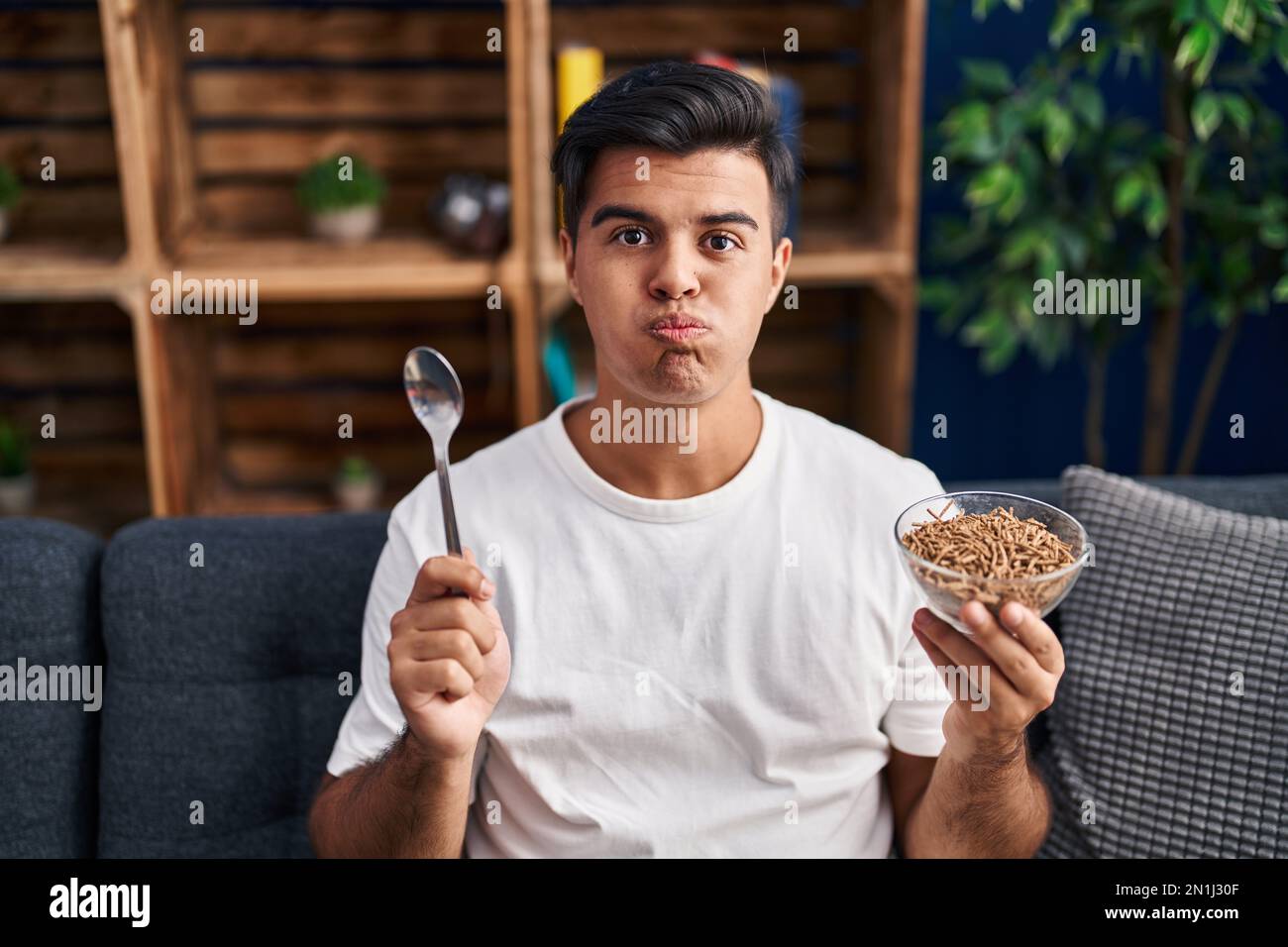 Hispanic man eating healthy whole grain cereals with spoon puffing ...