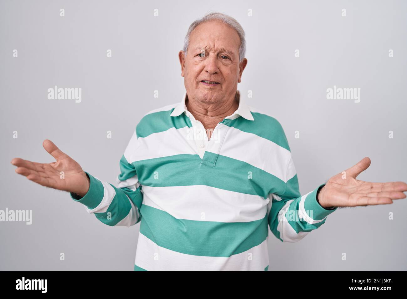 Senior man with grey hair standing over white background clueless and ...