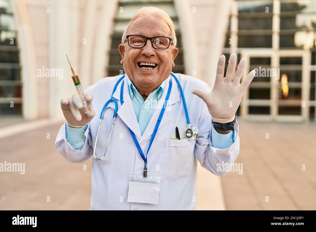 Senior doctor with grey hair holding syringe celebrating victory with ...