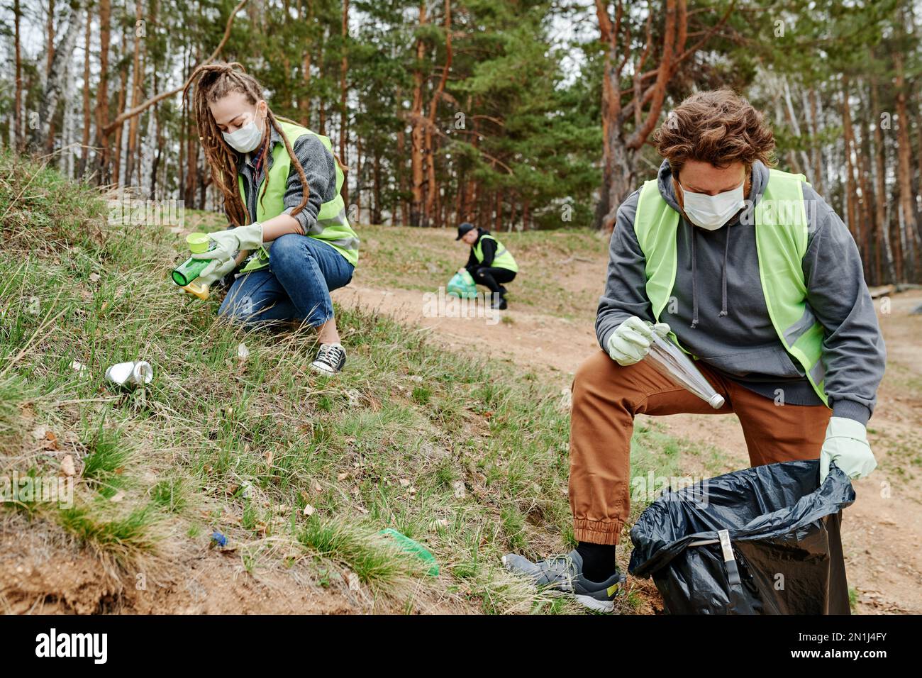 Volunteers collecting litter in park and putting in big black plastic ...