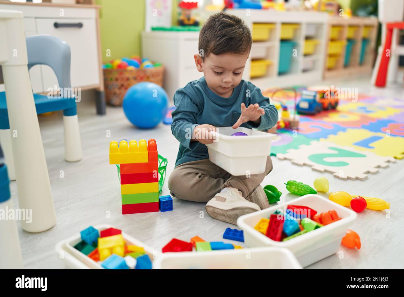 Adorable hispanic boy playing with construction blocks sitting on floor ...