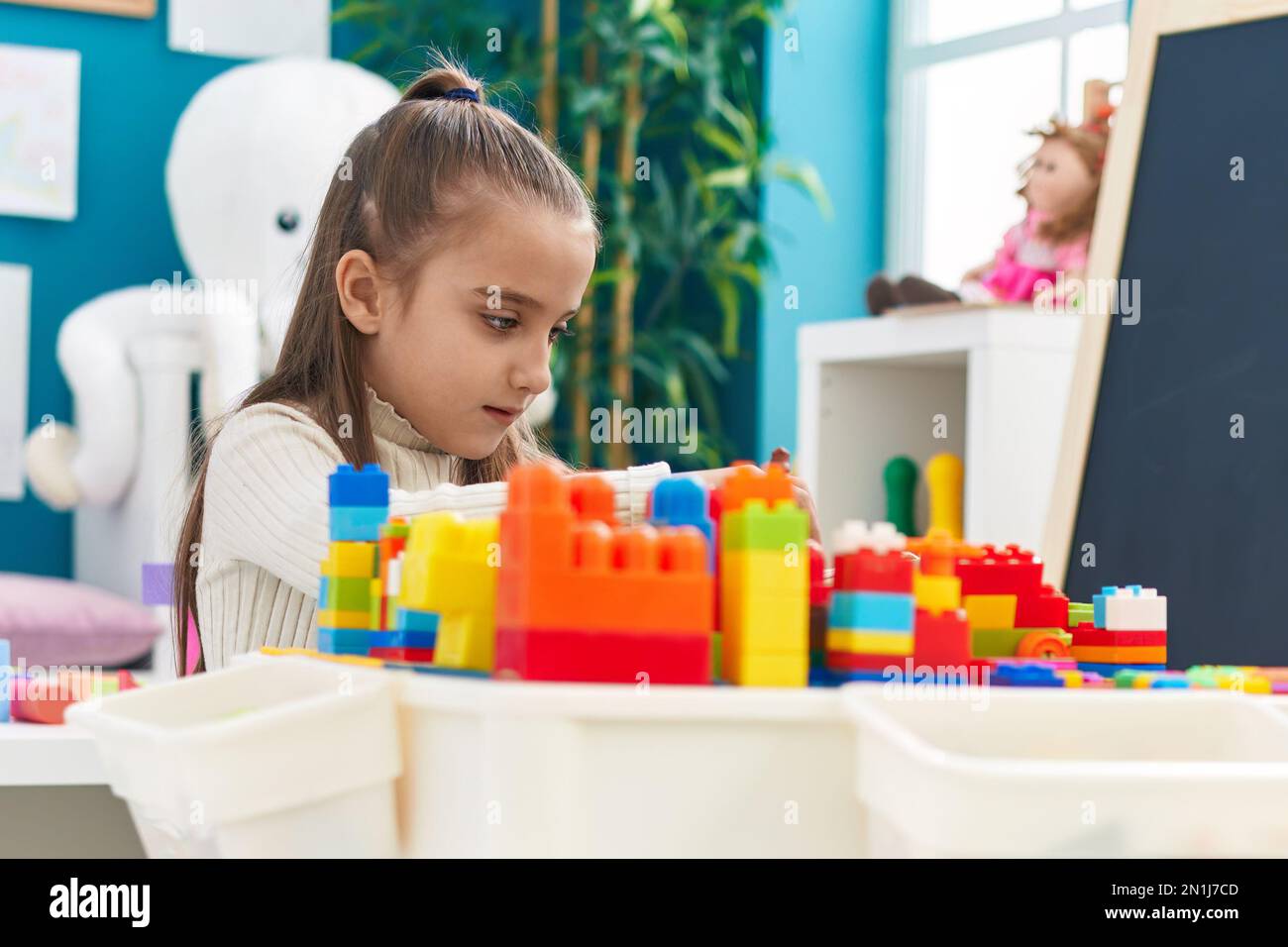 Adorable hispanic girl playing with construction blocks sitting on ...
