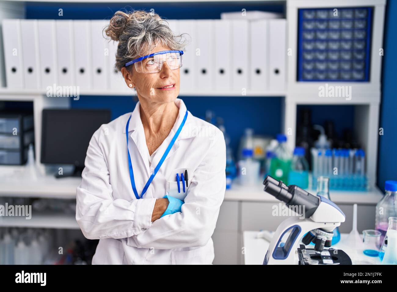 Middle age woman scientist sitting with arms crossed gesture at ...