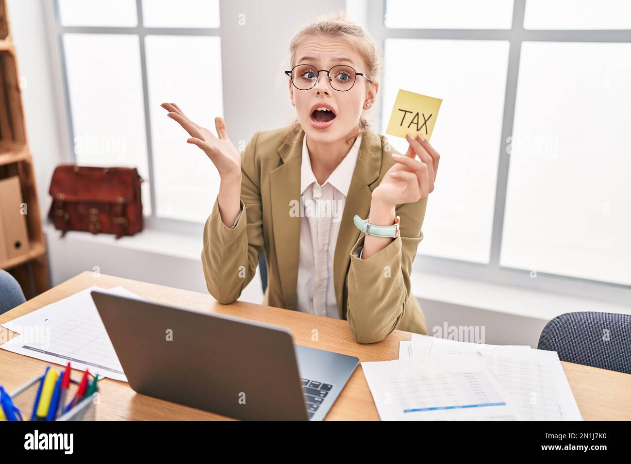 Young caucasian woman at the office calculating taxes celebrating ...