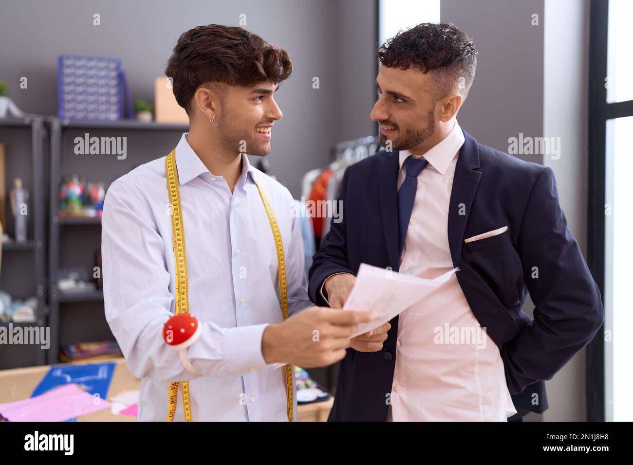 Two hispanic men tailor showing clothing design to client at atelier ...