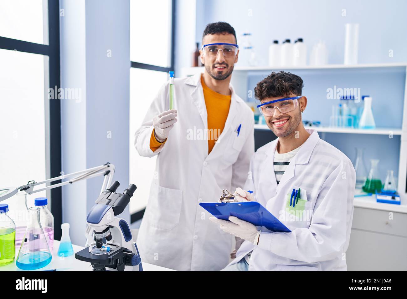 Two man scientists holding test tube write on clipboard working at ...