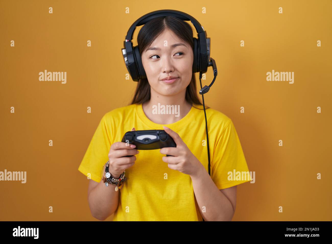 Chinese young woman playing video game holding controller smiling ...