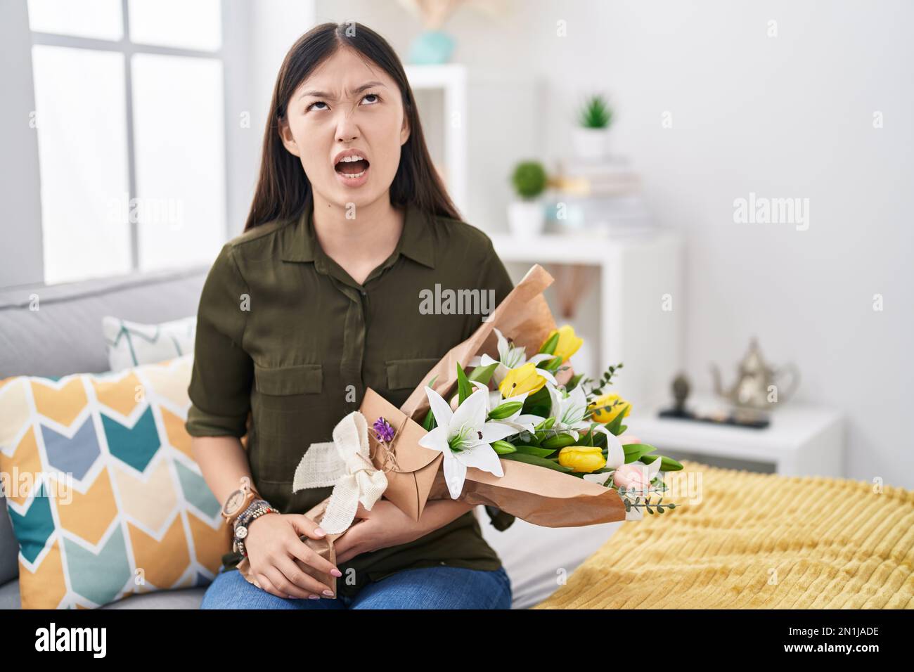 Chinese young woman holding bouquet of white flowers angry and mad ...