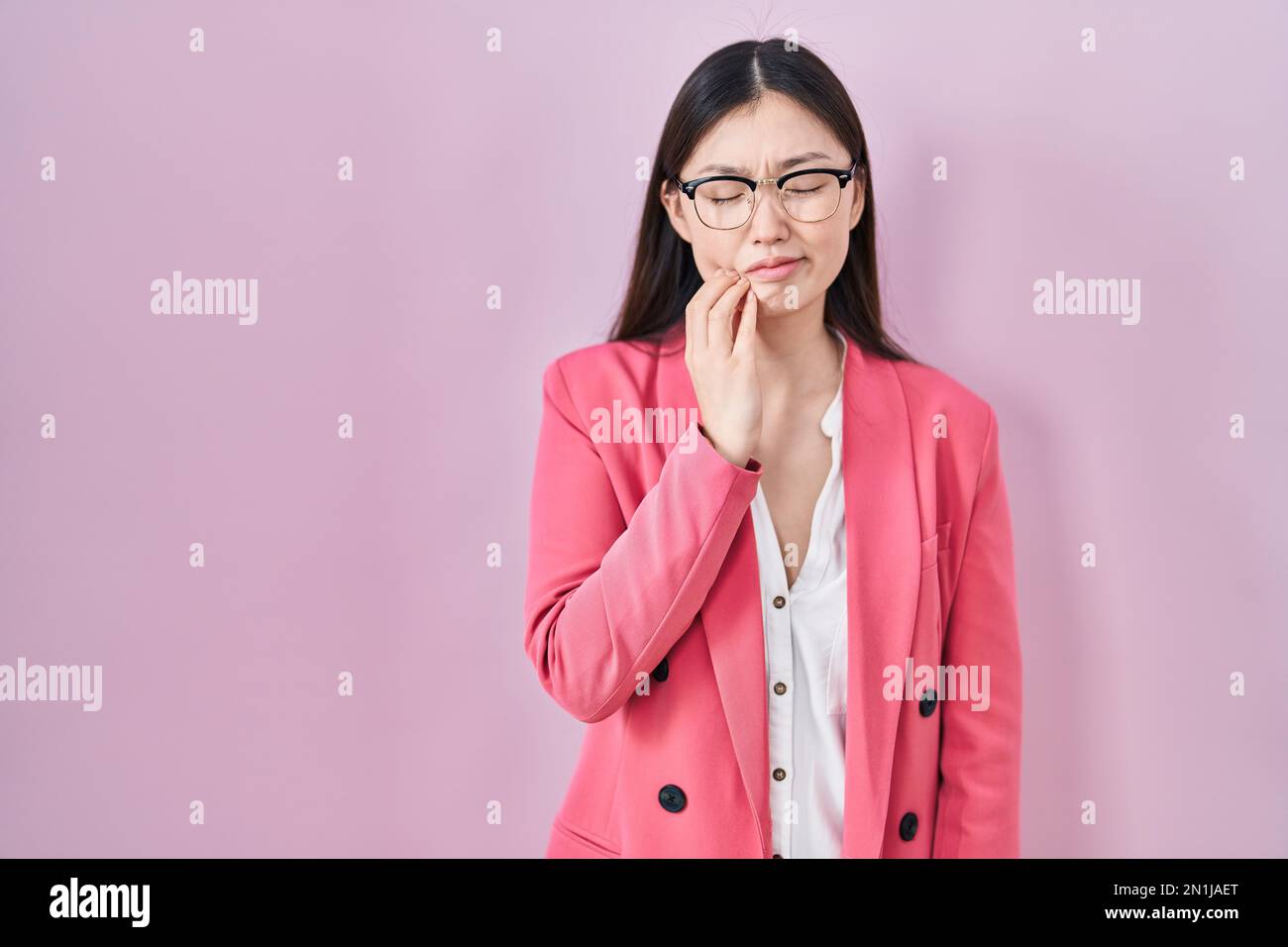 Chinese business young woman wearing glasses touching mouth with hand ...