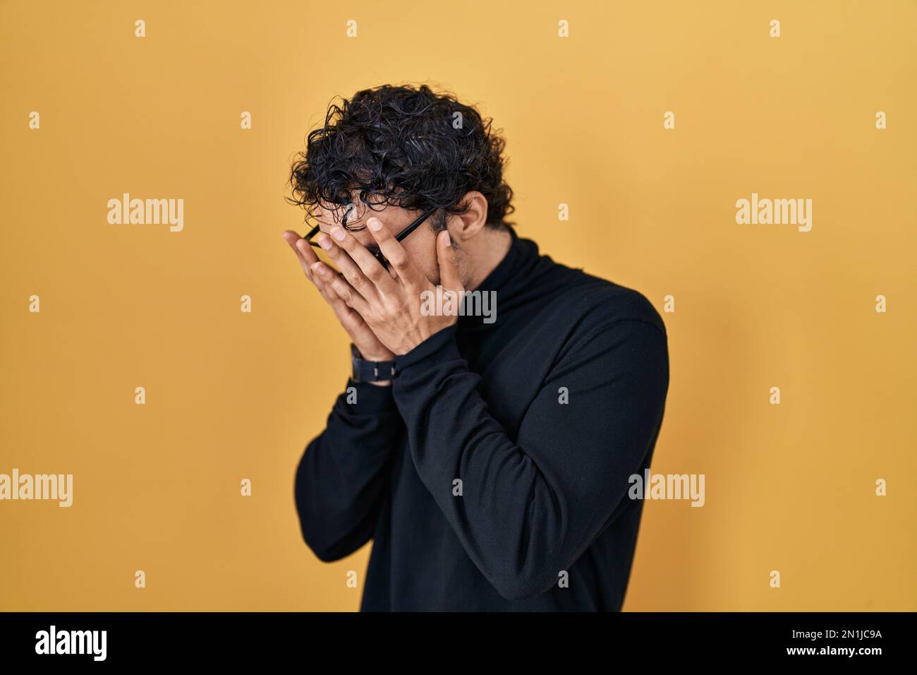 Hispanic man standing over yellow background with sad expression ...