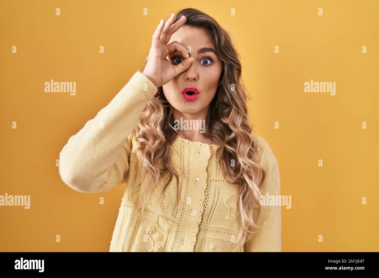 Young caucasian woman standing over yellow background doing ok gesture ...