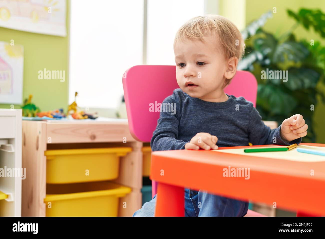 Adorable blond toddler preschool student sitting on table drawing on ...