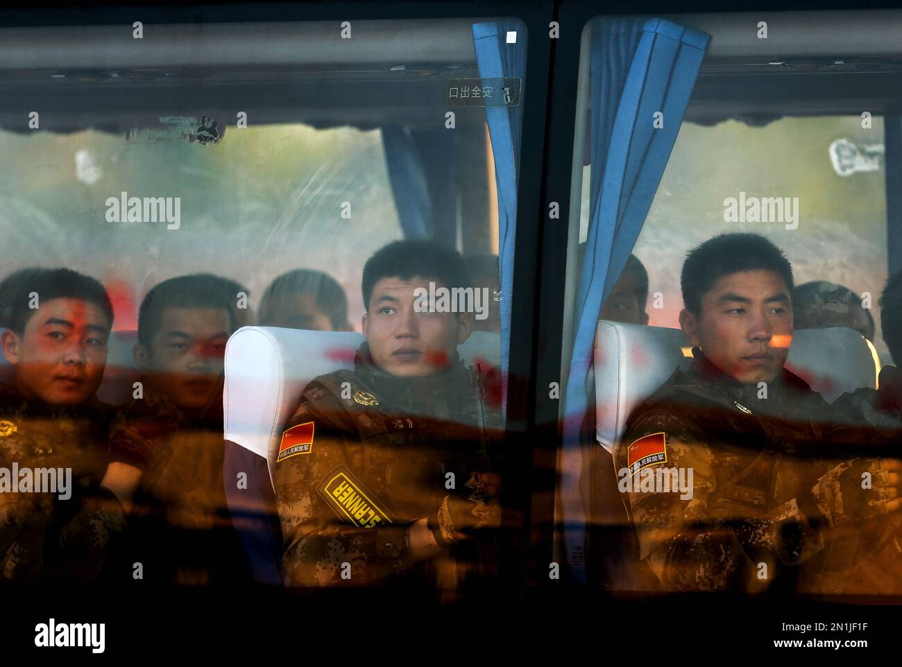 Chinese People's Liberation Army troops look out from a bus as they ...