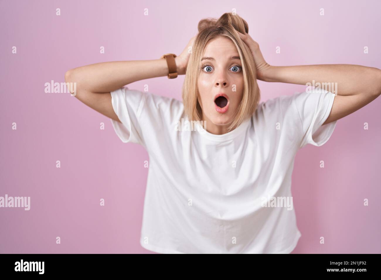 Young caucasian woman standing over pink background crazy and scared ...