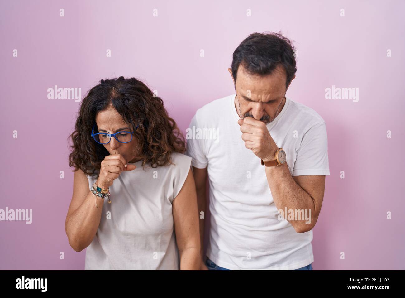 Middle age hispanic couple together over pink background feeling unwell ...