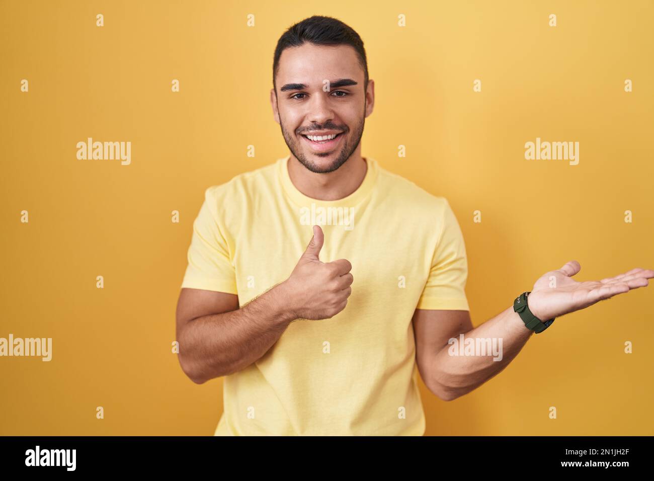 Young hispanic man standing over yellow background showing palm hand ...