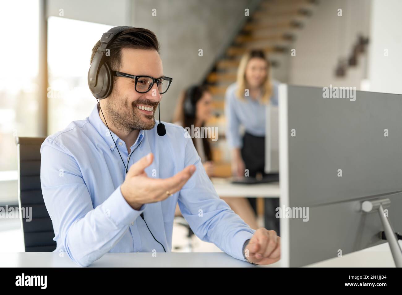 Friendly handsome male call centre executive worker talking to client ...