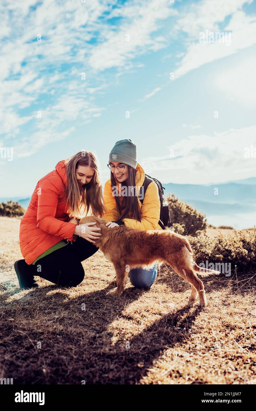 two friends are playing with a dog in nature Stock Photo - Alamy