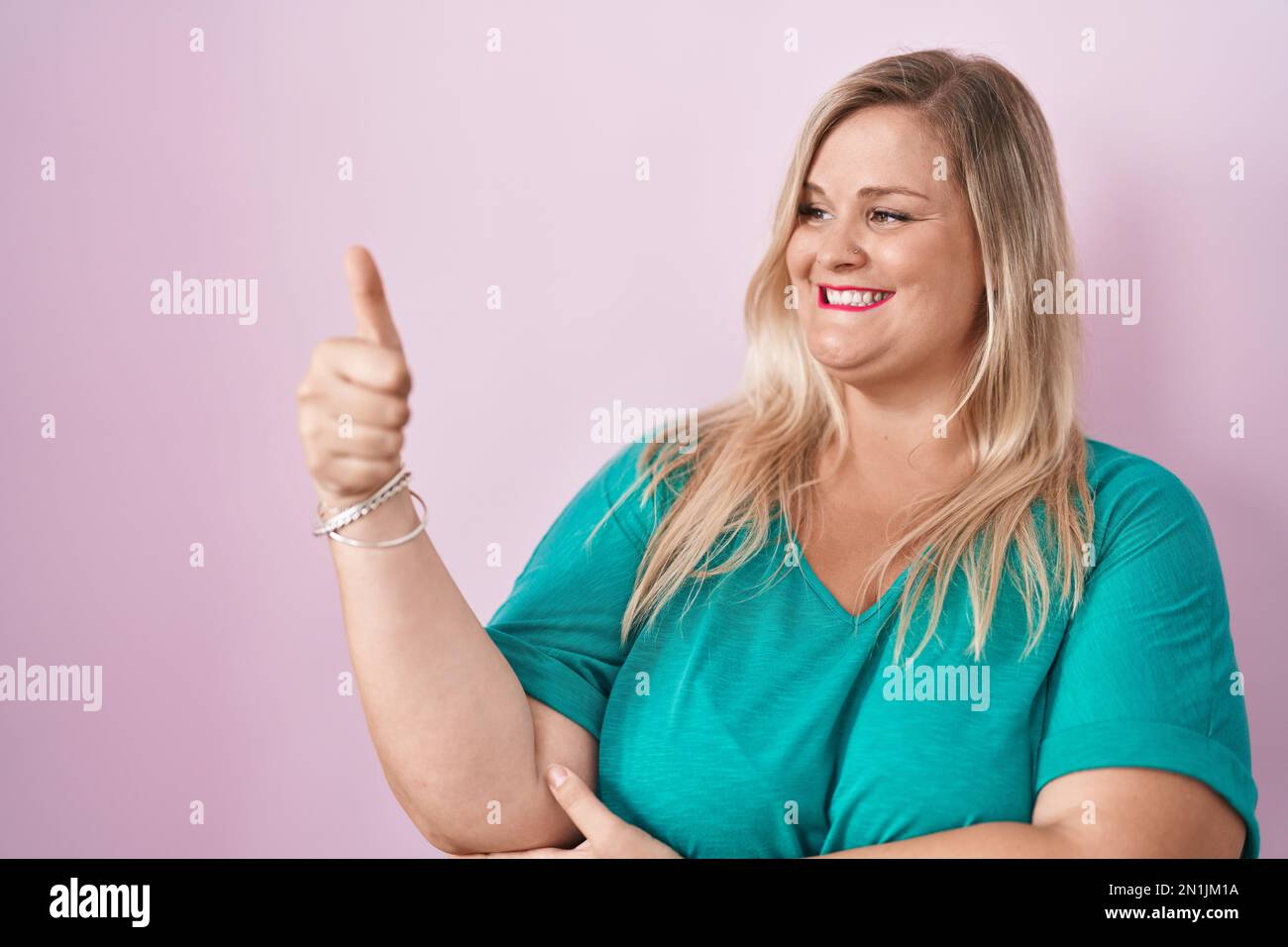 Caucasian plus size woman standing over pink background looking proud ...