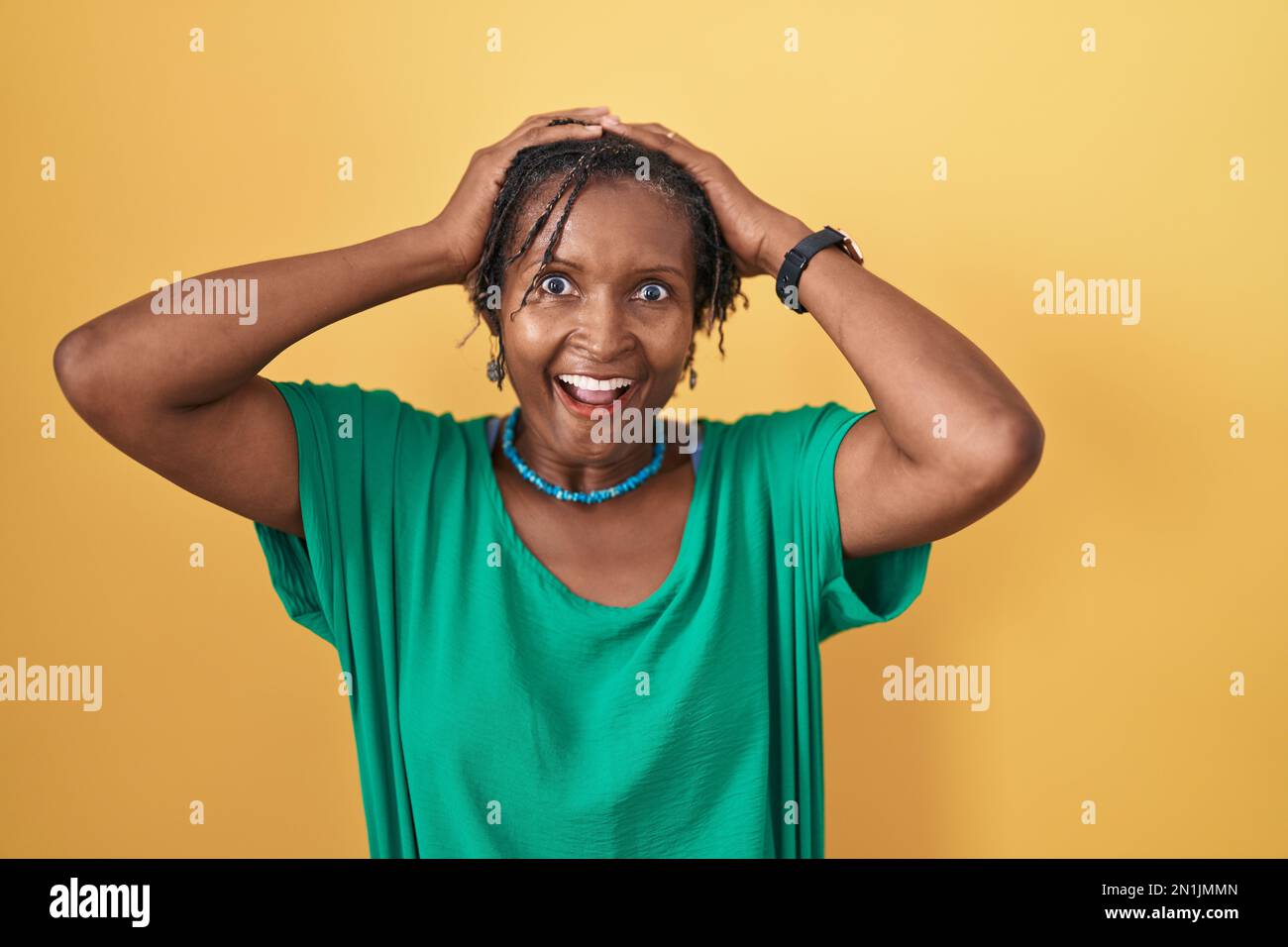 African woman with dreadlocks standing over yellow background crazy and ...