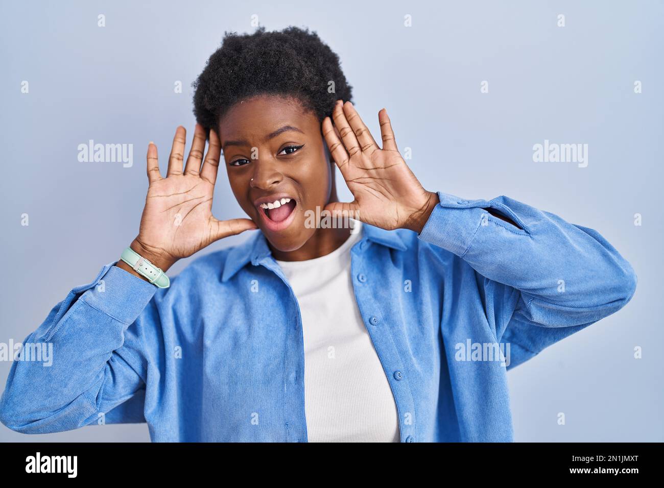 African american woman standing over blue background smiling cheerful ...