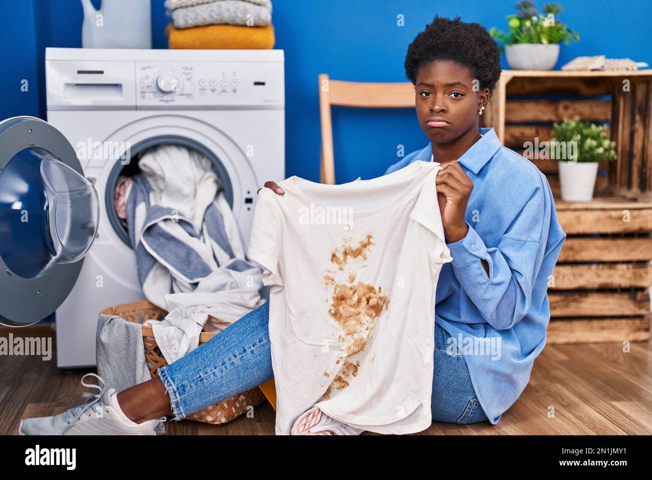 African american woman holding t shirt with dirty stain depressed and ...