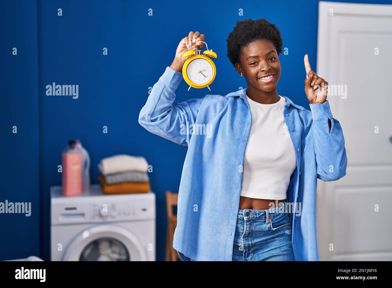African american woman waiting for laundry surprised with an idea or ...