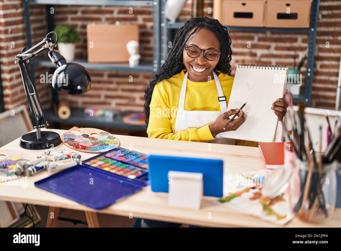 African american woman artist having online paint lesson at art studio ...
