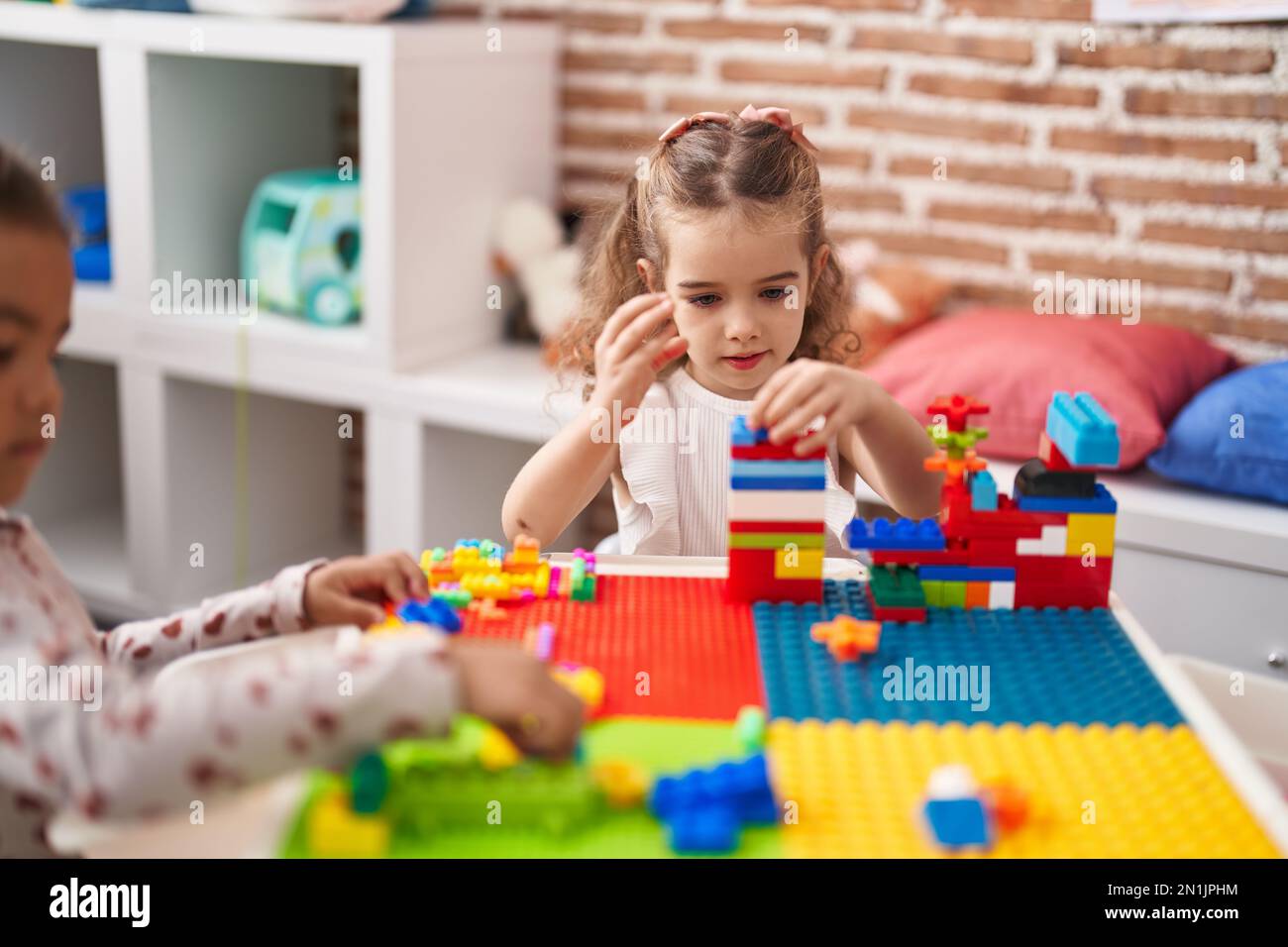 Two kids playing with construction blocks sitting on table at ...
