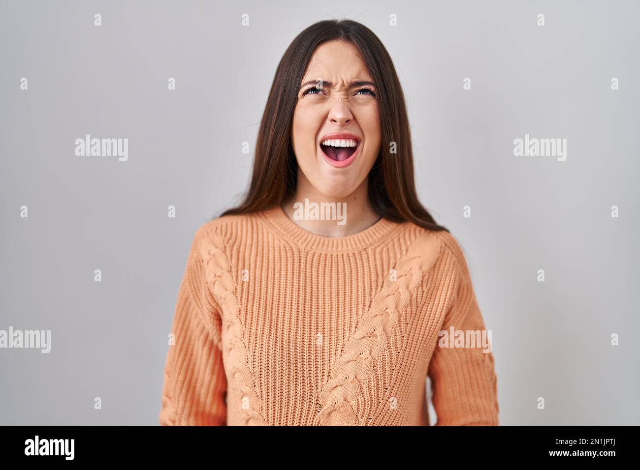 Young brunette woman standing over white background angry and mad ...